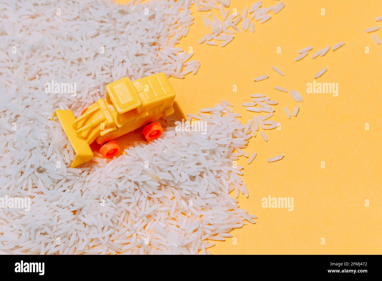 From above of small plastic toy tractor collecting pile of rice grains ...