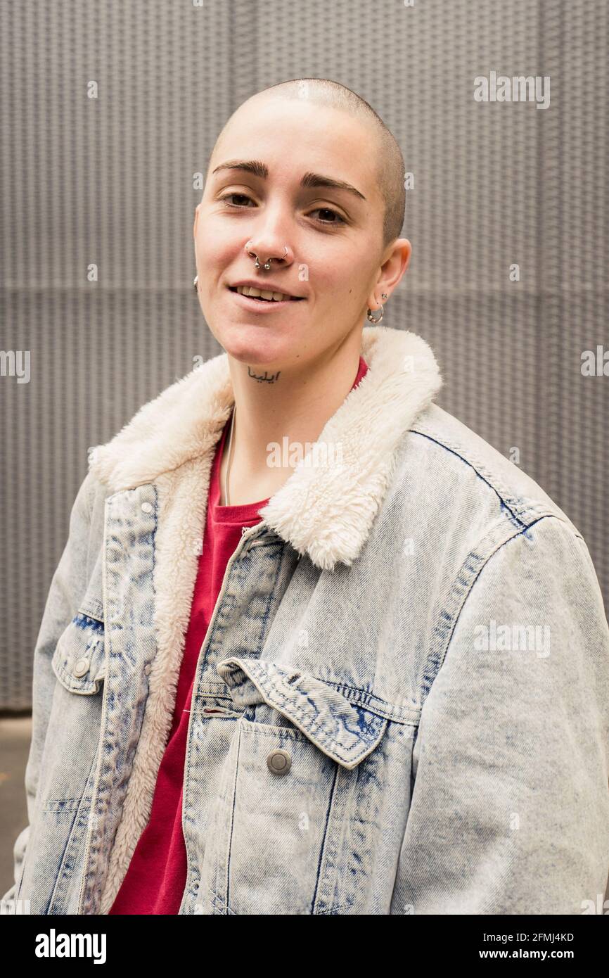 Happy transgender person in denim jacket with fur and earrings looking ...