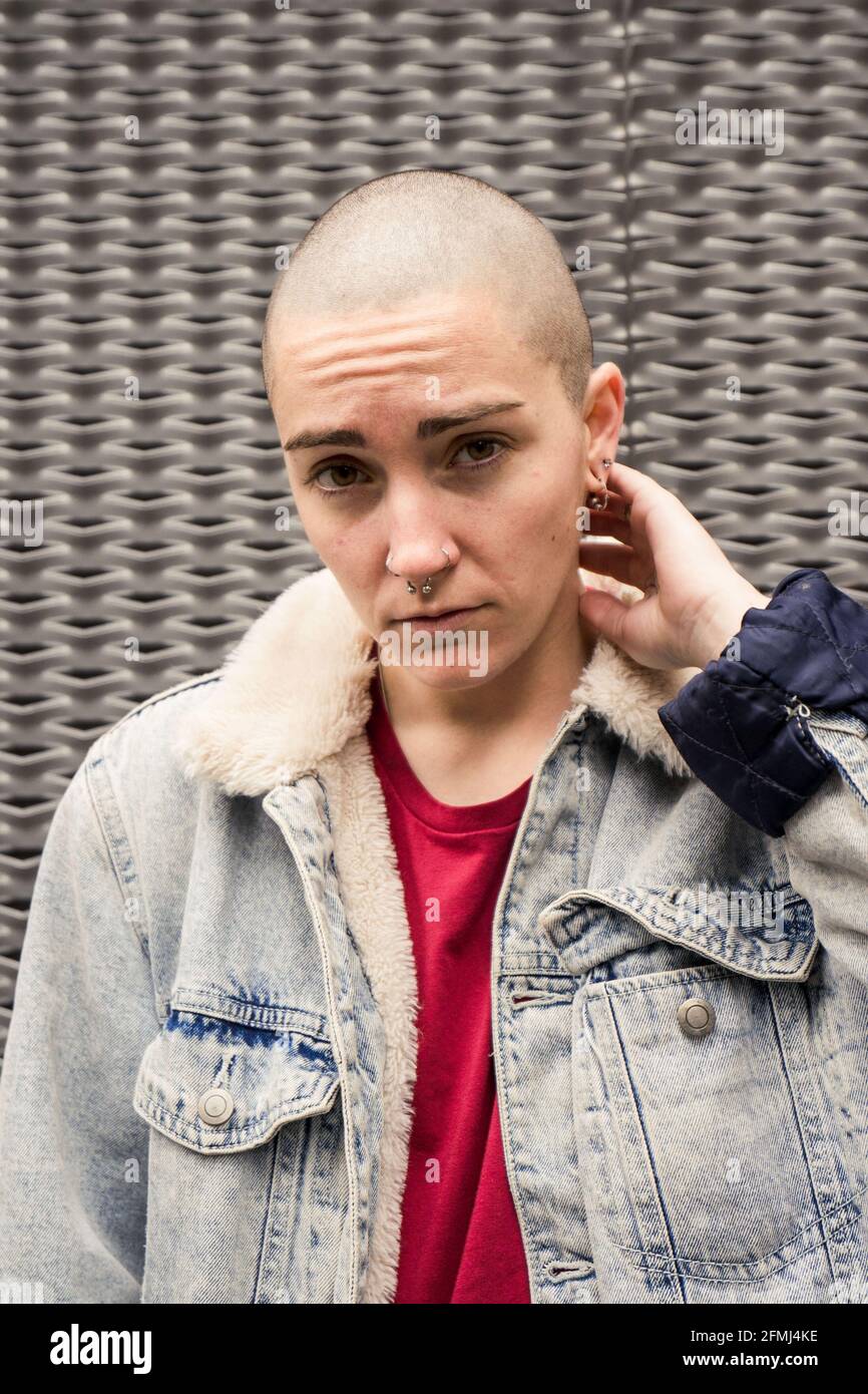 Transgender person in denim jacket with fur and earrings looking at ...