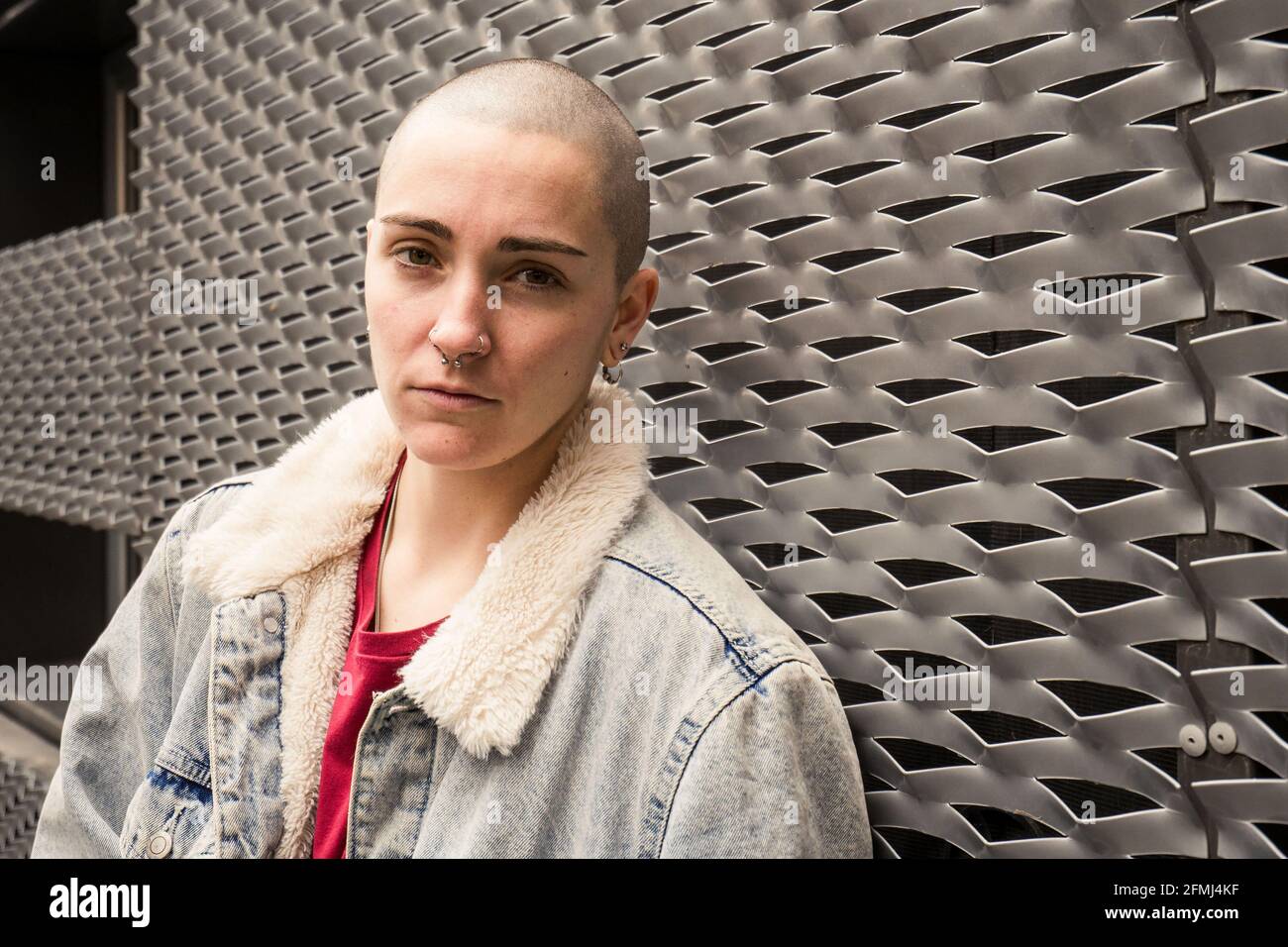 Transgender person in denim jacket with fur and earrings looking at ...