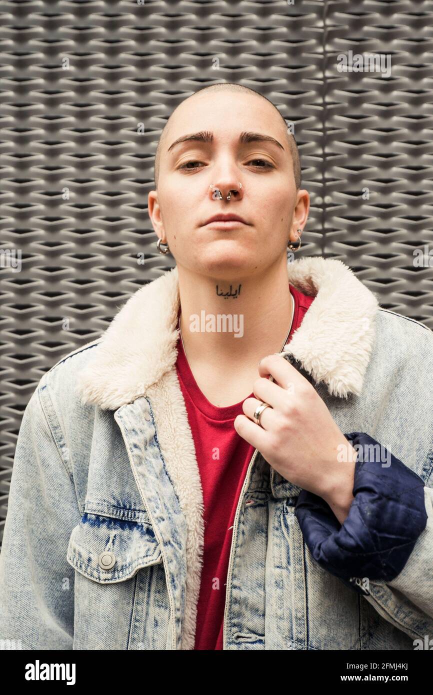 Transgender person in denim jacket with fur and earrings looking at ...