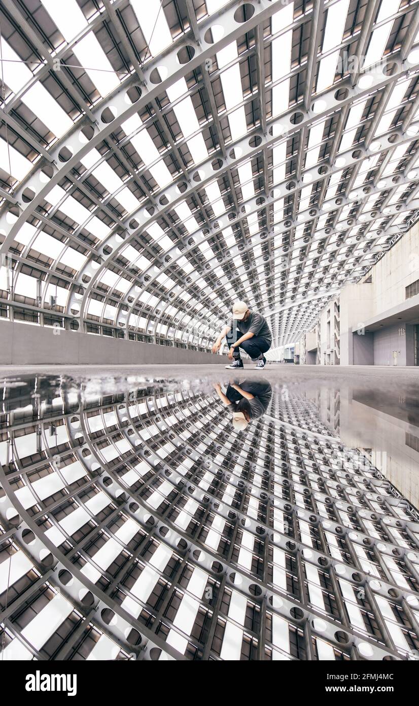 Full body faceless male sitting on haunches in creative pedestrian ...