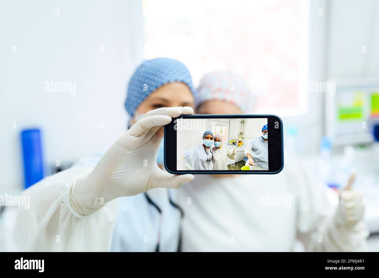 Anonymous female doctors in uniforms with thumb up taking self portrait ...