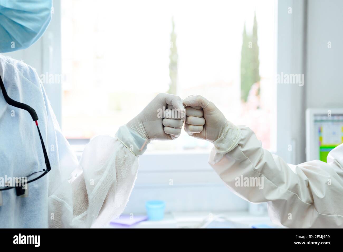 Anonymous doctors in uniforms greeting each other with high five at ...