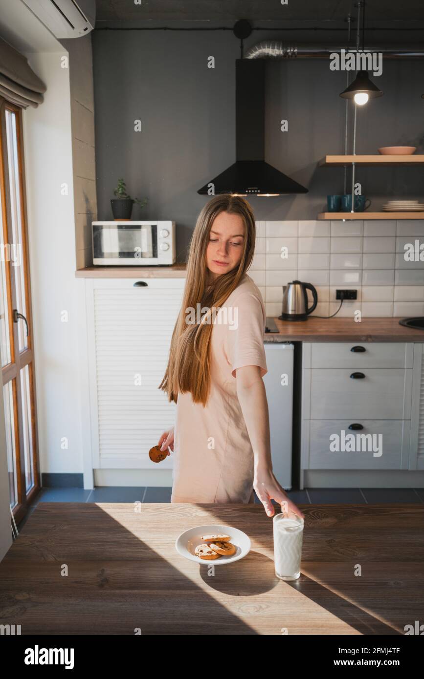 Side view of millennial female looking down at table with glass of milk ...