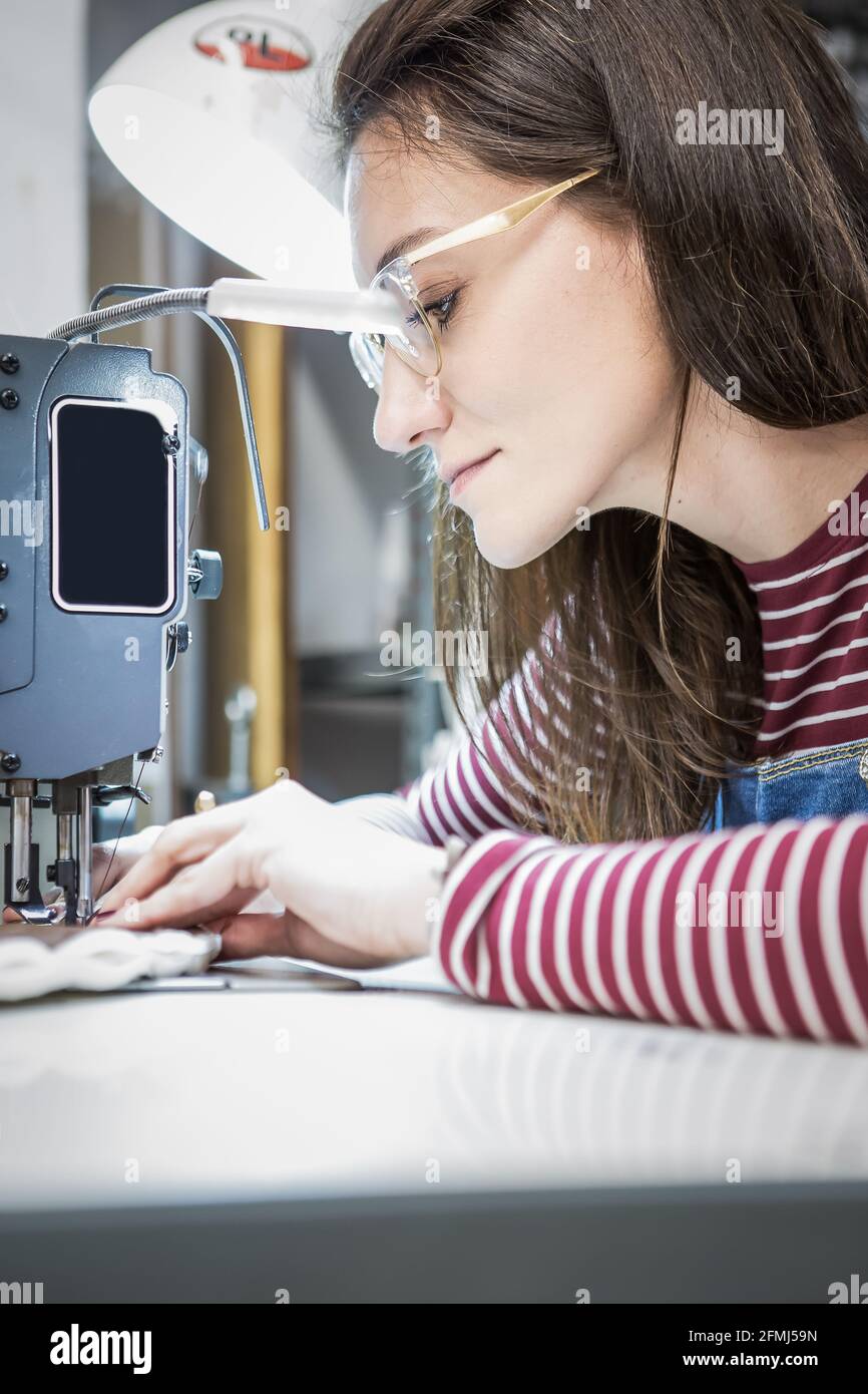 Side view female artisan using sewing machine while creating upholstery ...