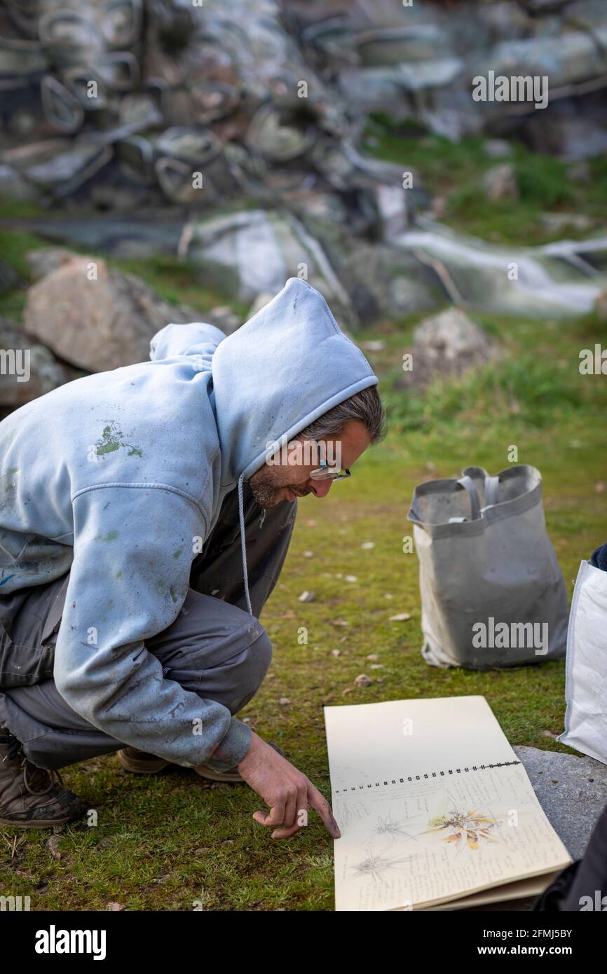 Side view male artist turning page of album with sketches in nature ...