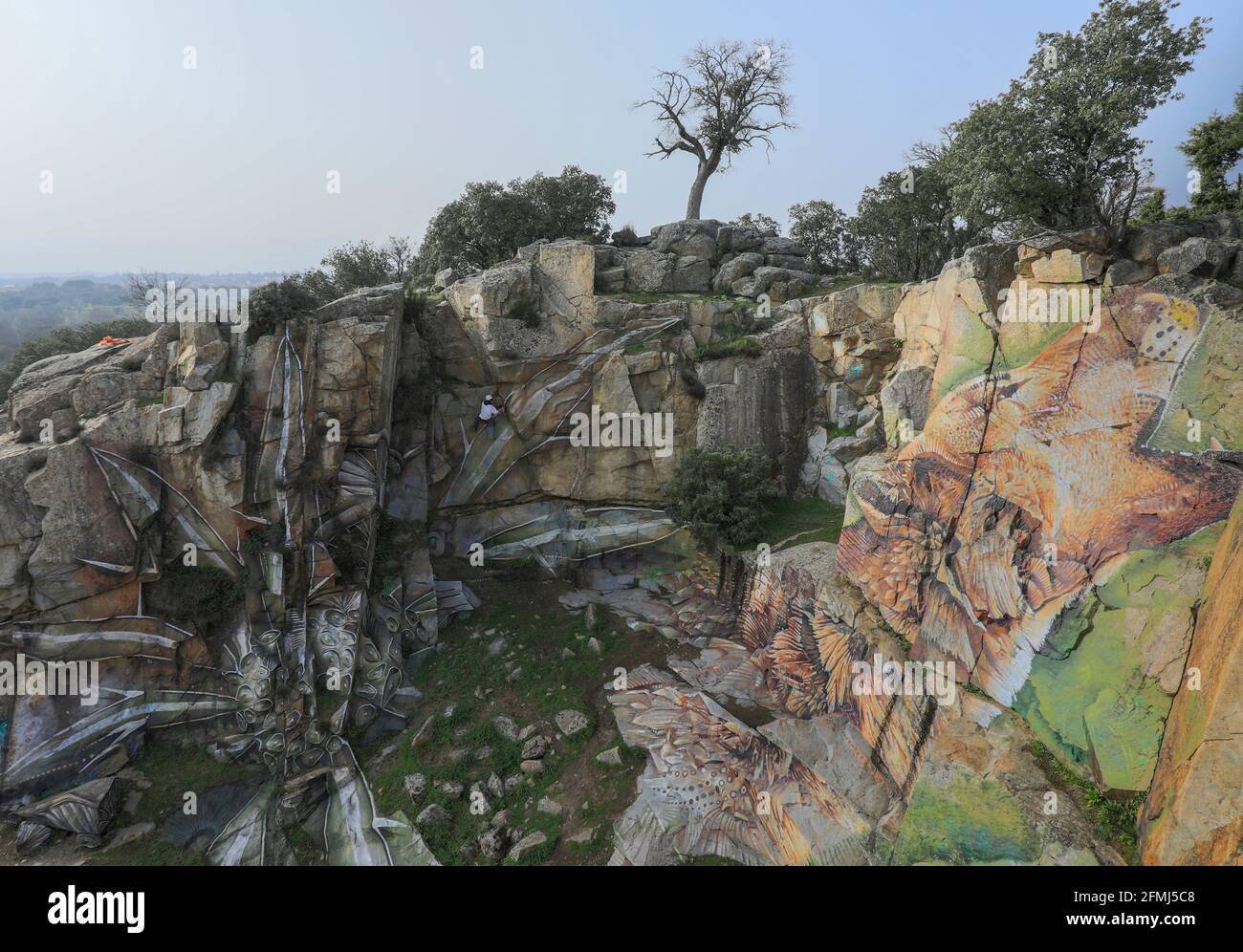 Drone view of man in helmet hanging on rope while painting graffiti on ...