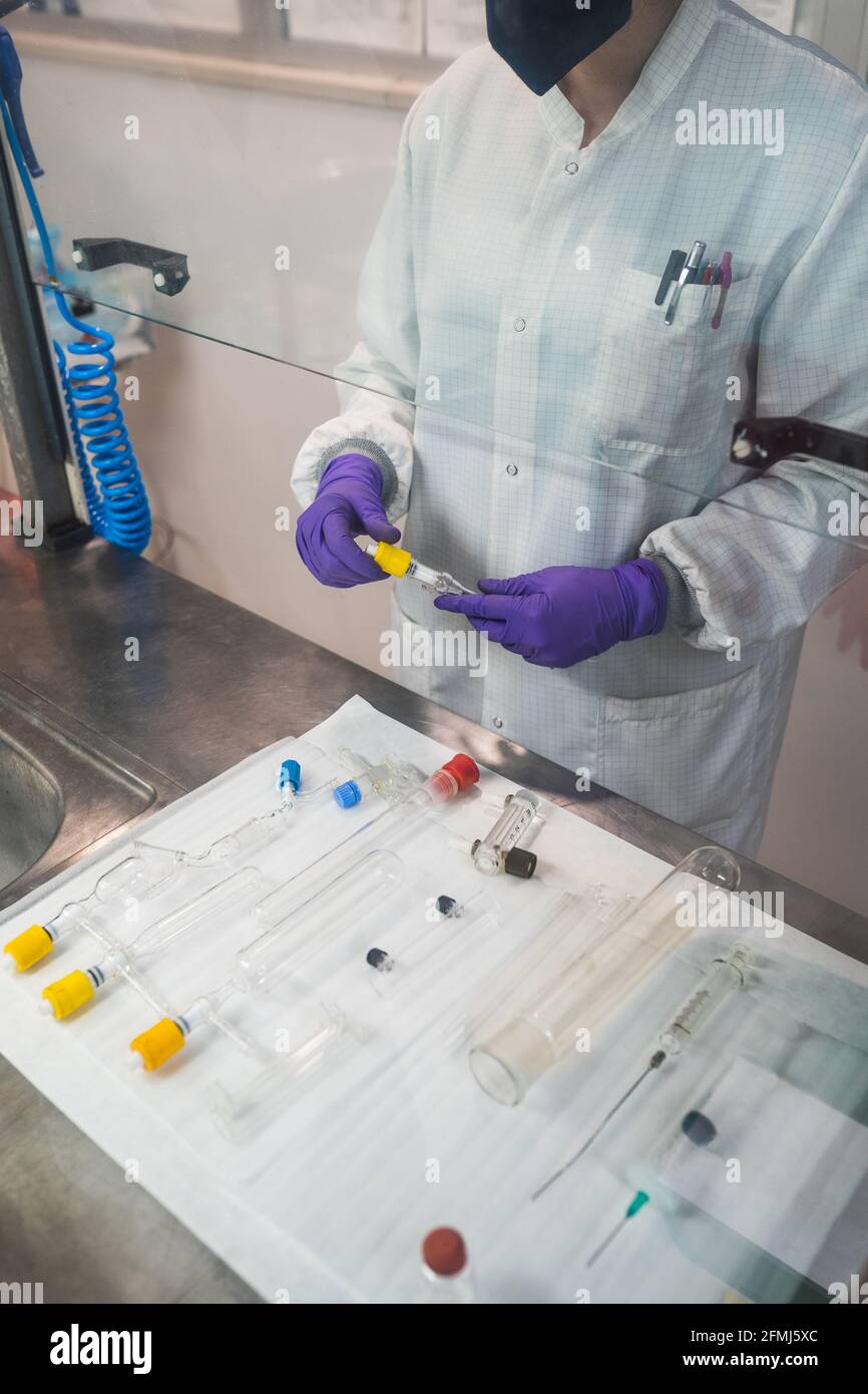 Crop anonymous competent researcher in white robe latex gloves and face ...