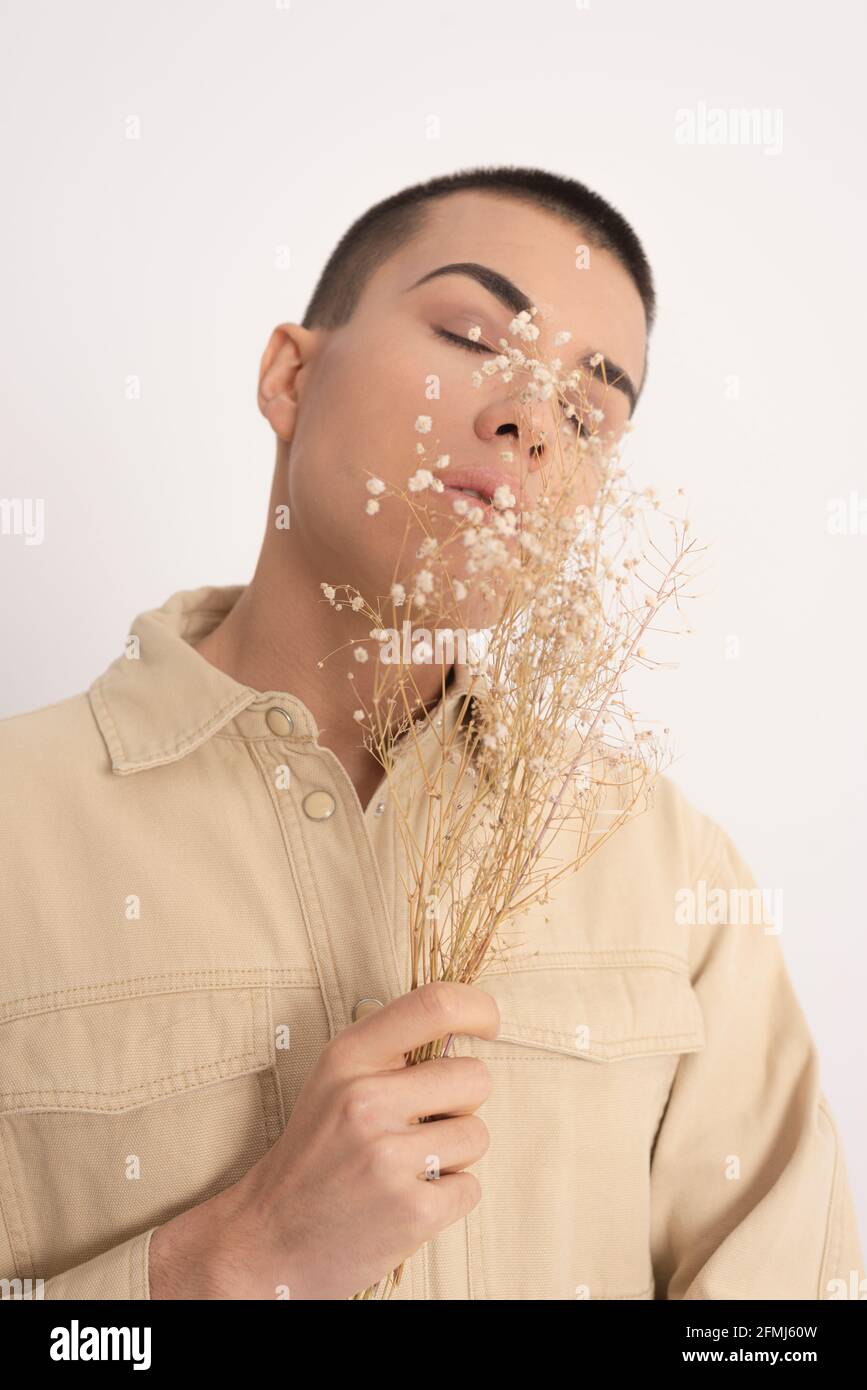 Androgynous male model in trendy shirt and with bunch of dried plants ...
