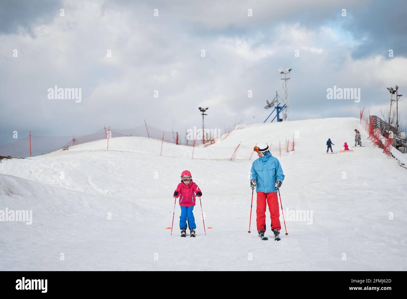 Full body faceless parent in warm sportswear and helmet teaching little ...