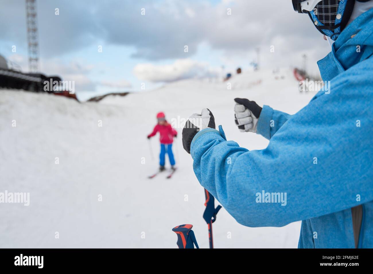 Faceless parent in warm sportswear teaching little kid to ski alongside ...