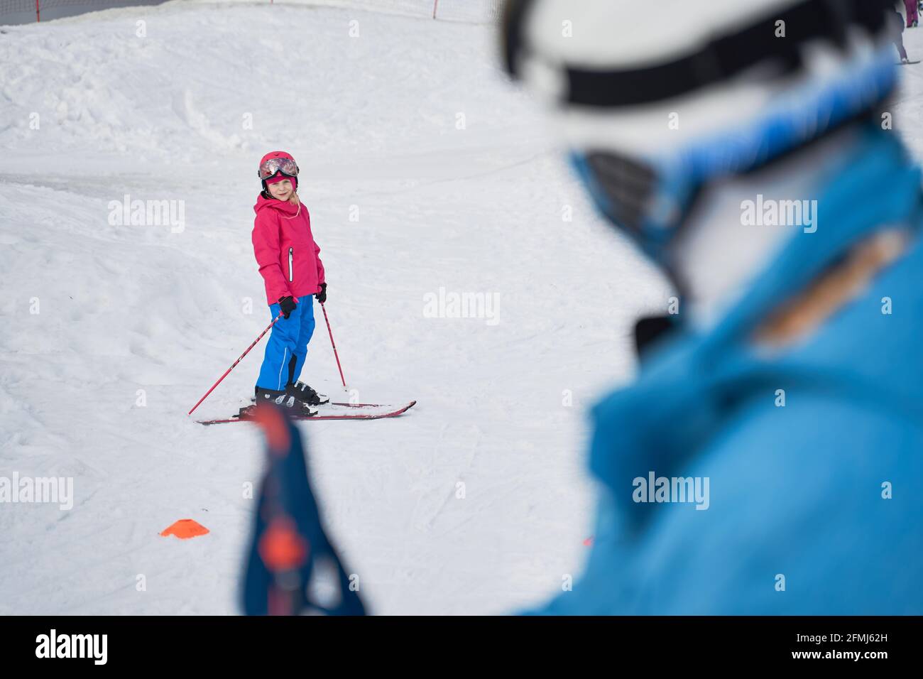 Side view faceless parent in warm sportswear and helmet teaching little ...