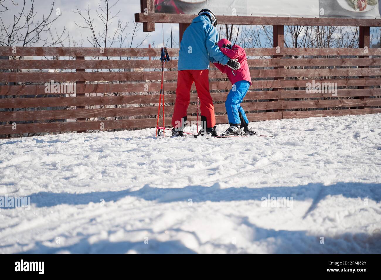 Full body faceless parent in warm sportswear and helmet teaching little ...