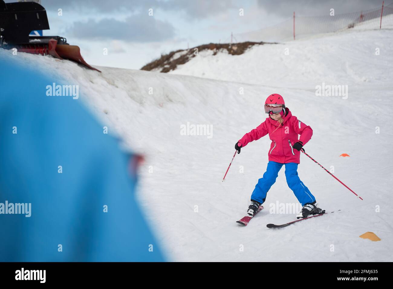 Faceless parent in warm sportswear teaching little kid to ski alongside ...