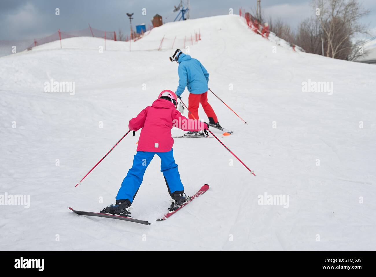 Full body faceless parent in warm sportswear and helmet teaching little ...