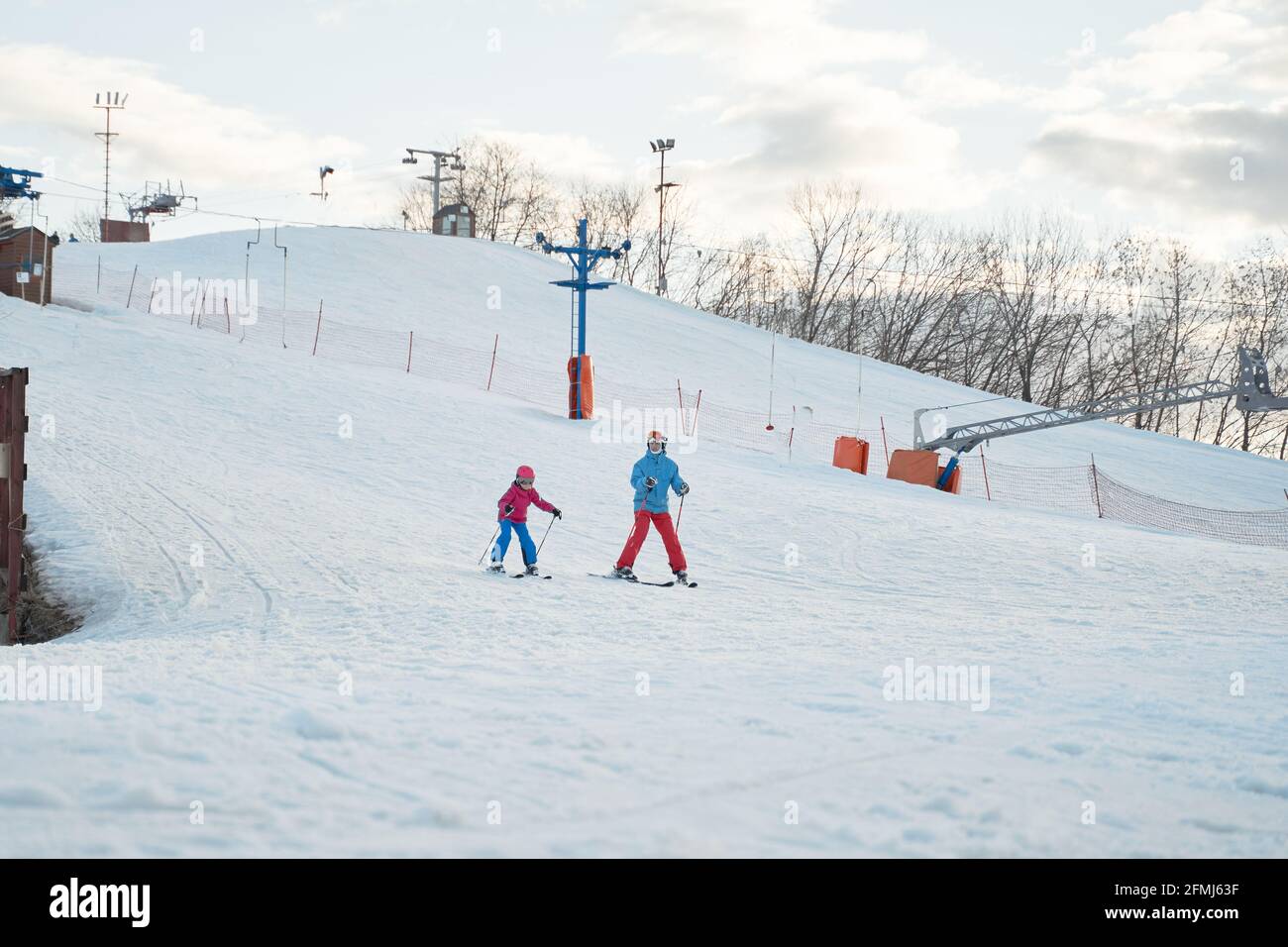 Full body faceless parent in warm sportswear and helmet teaching little ...
