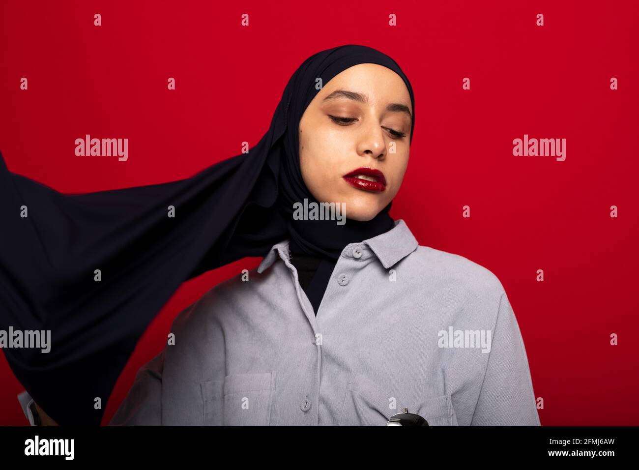 Attractive young Islamic female in casual shirt and dark hijab standing ...