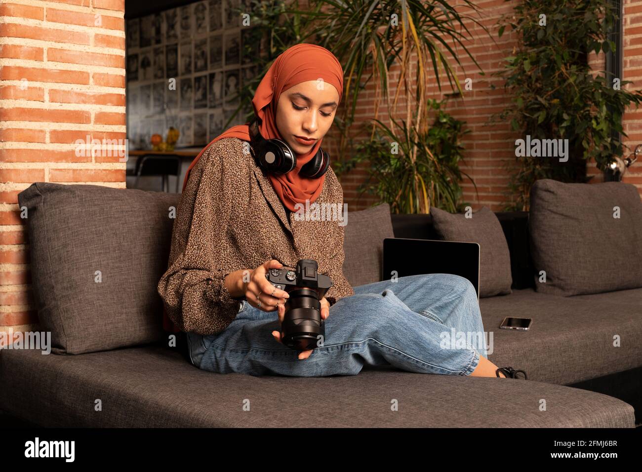 Concentrated young Muslim female in modest wear hijab and headphones ...
