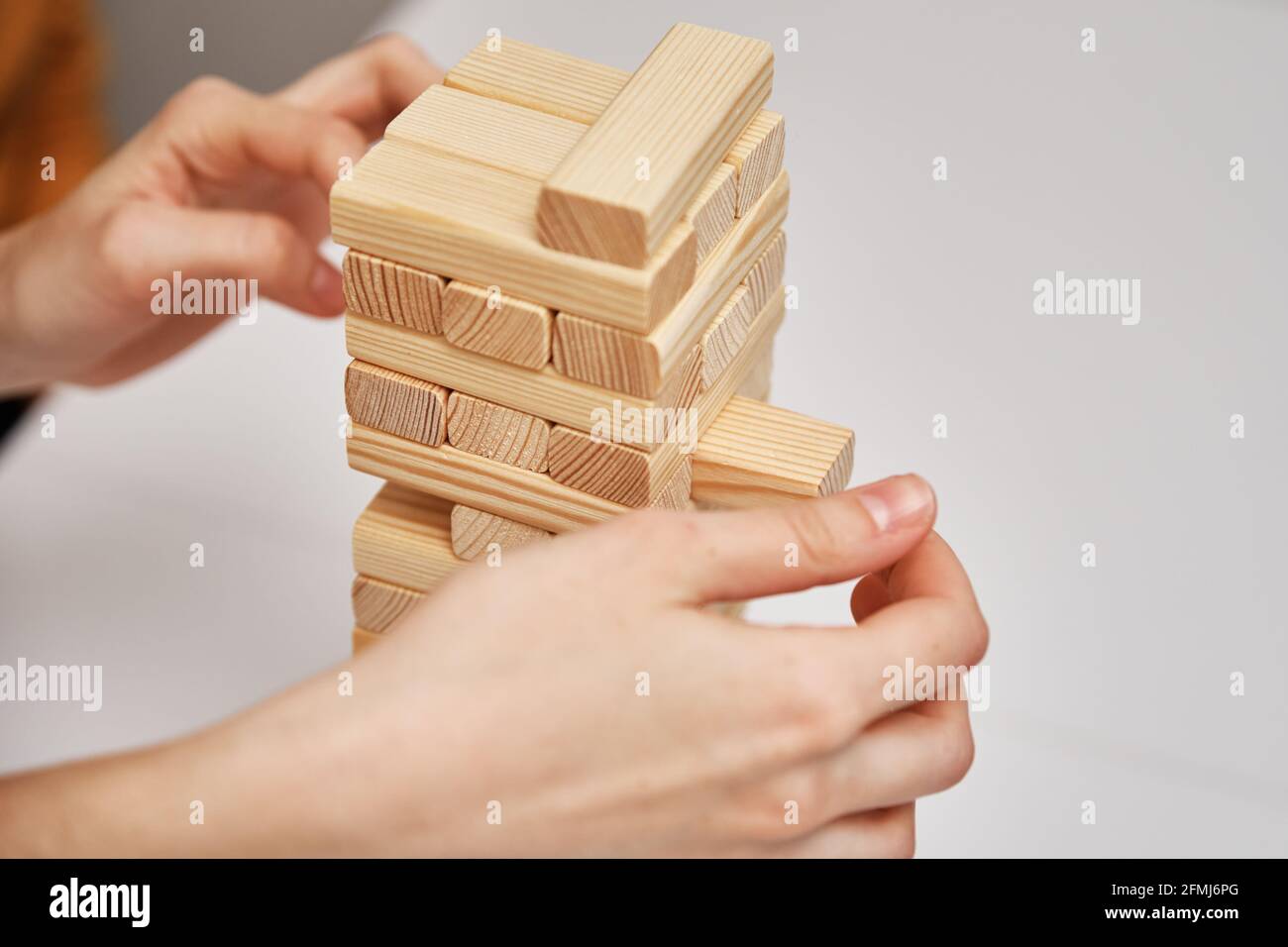 Hand take one block from wooden tower on white background. Family ...