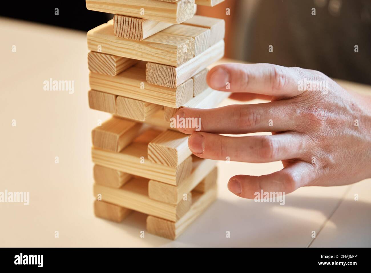 Hand take one block from wooden tower on white background. Family ...