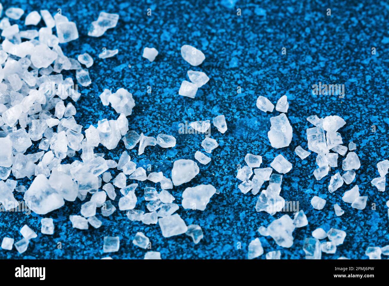Coarse salt crystals on a blue table. sea salt. Background for ...