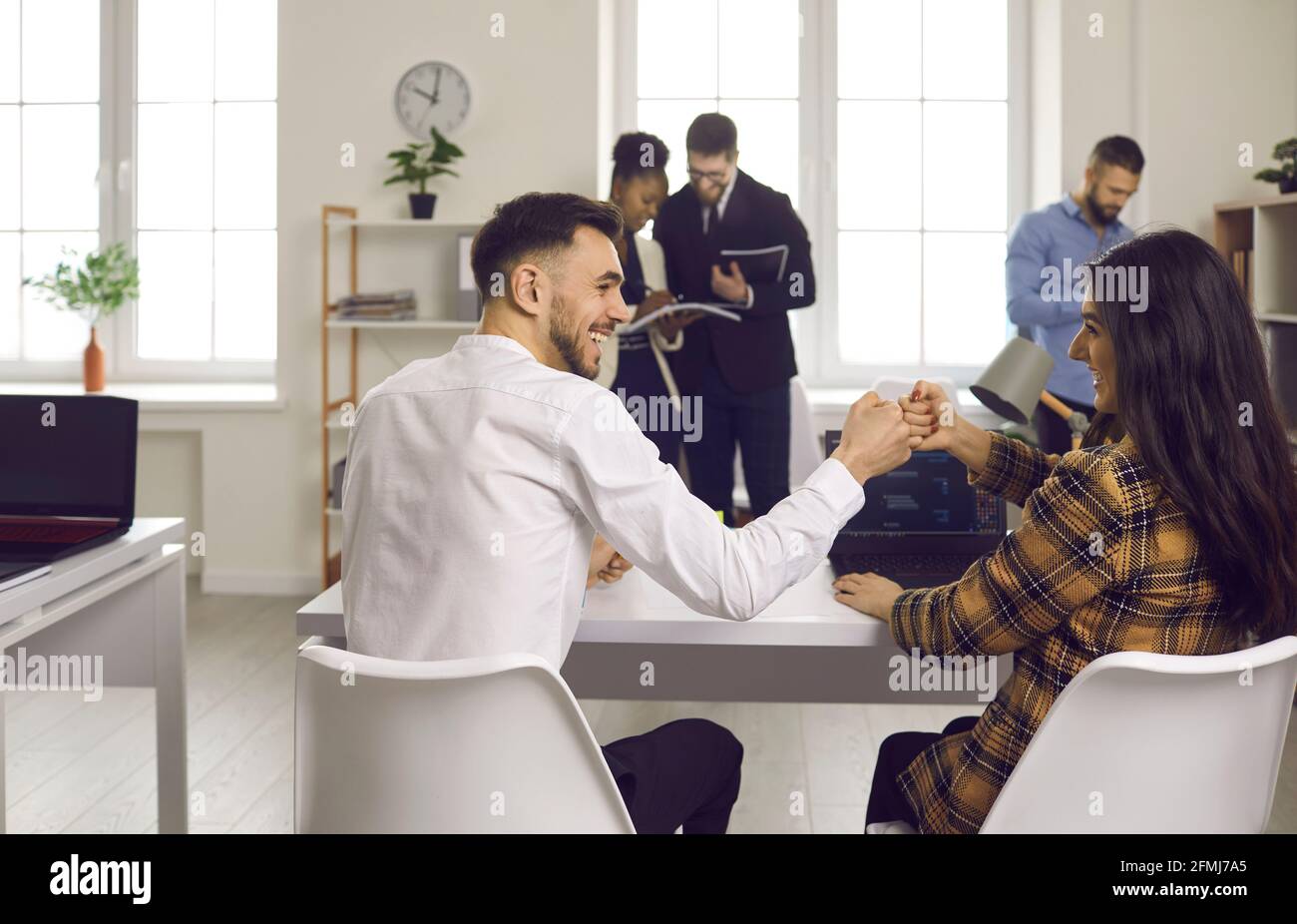 Two business people or colleagues making a deal and fist bumping ...