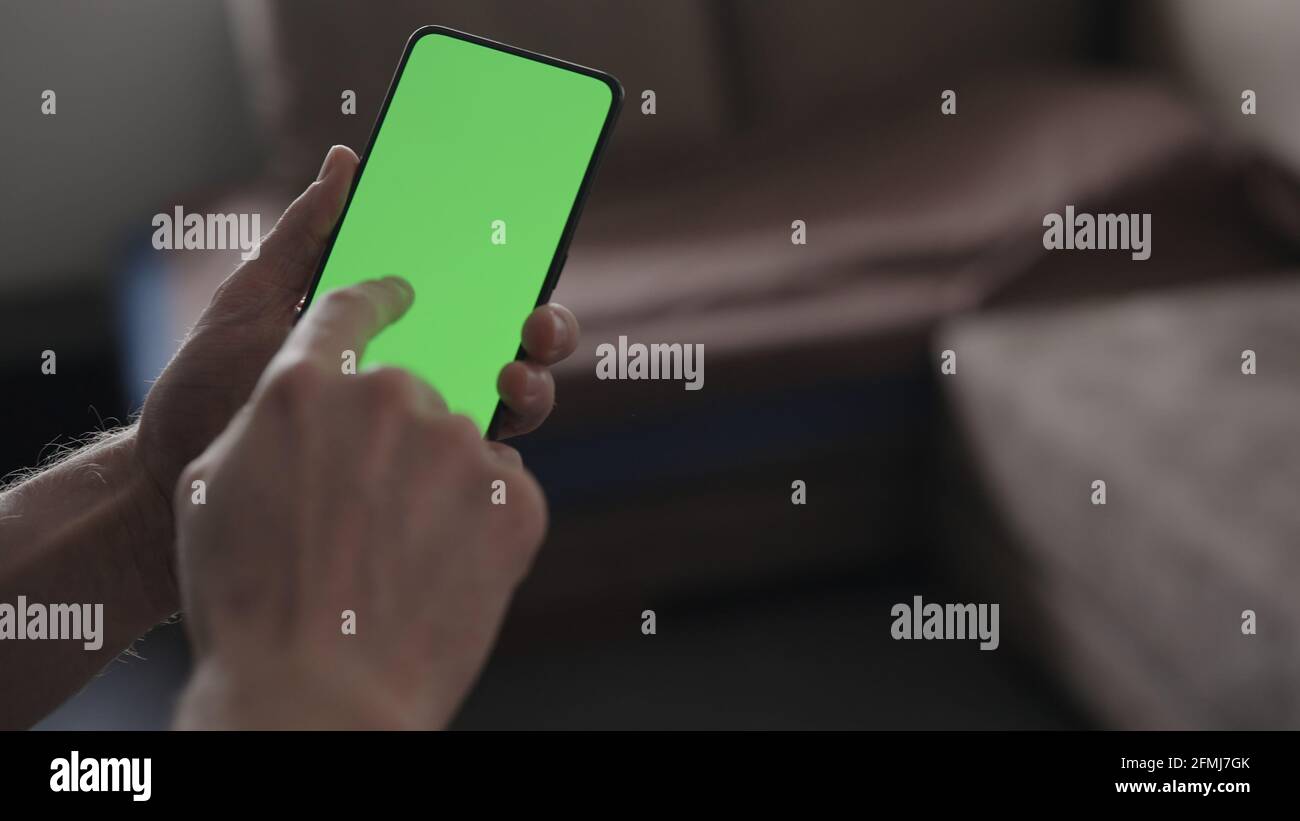 Man use smartphone with green screen while standing in living room ...