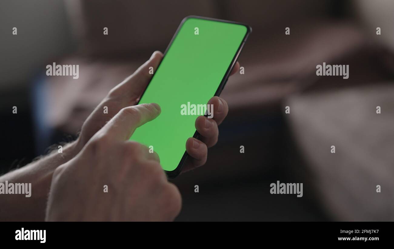 Man use smartphone with green screen while standing in living room ...