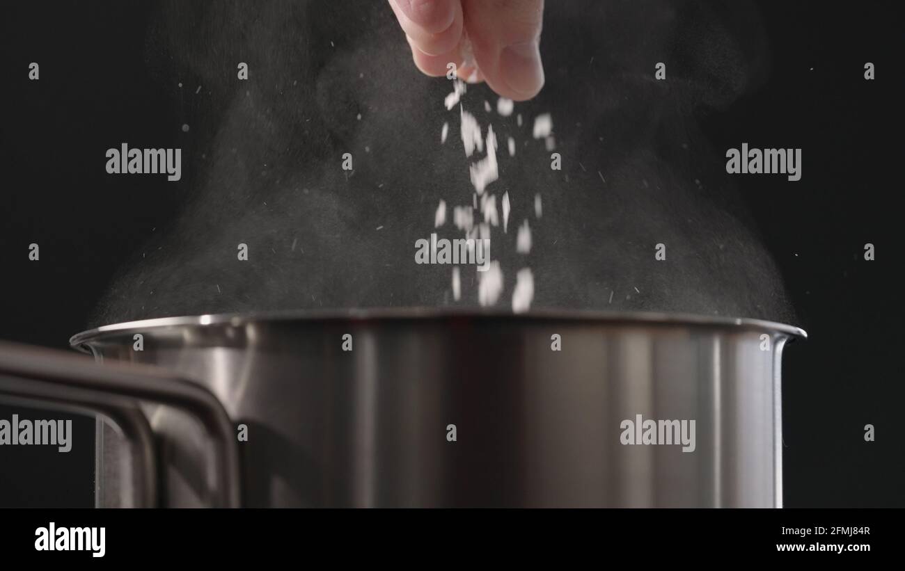 man salting boiling water in saucepan, wide photo Stock Photo - Alamy