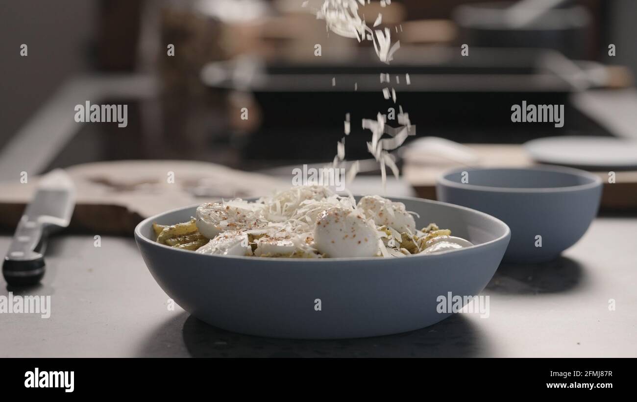 add grated cheese to penne pasta with pesto and mozzarella in blue bowl ...