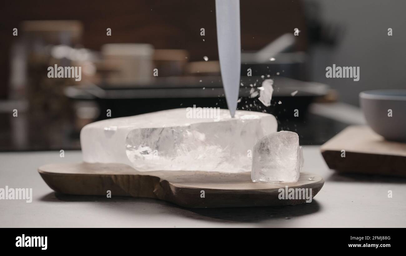 man breaking ice block with knife on olive wood board, wide photo Stock ...