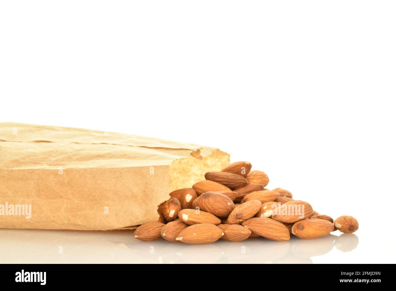 Several grains of peeled raw, organic almonds with a paper bag, close ...
