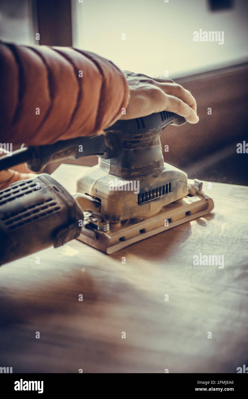 Man sanding wood plank using electric sand machine Stock Photo - Alamy