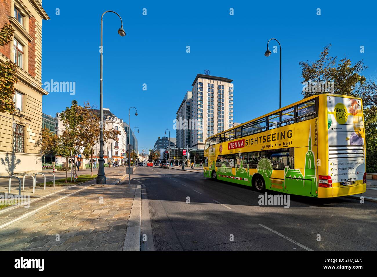 Yellow sightseeing tour bus under blue sky on the street of Vienna ...