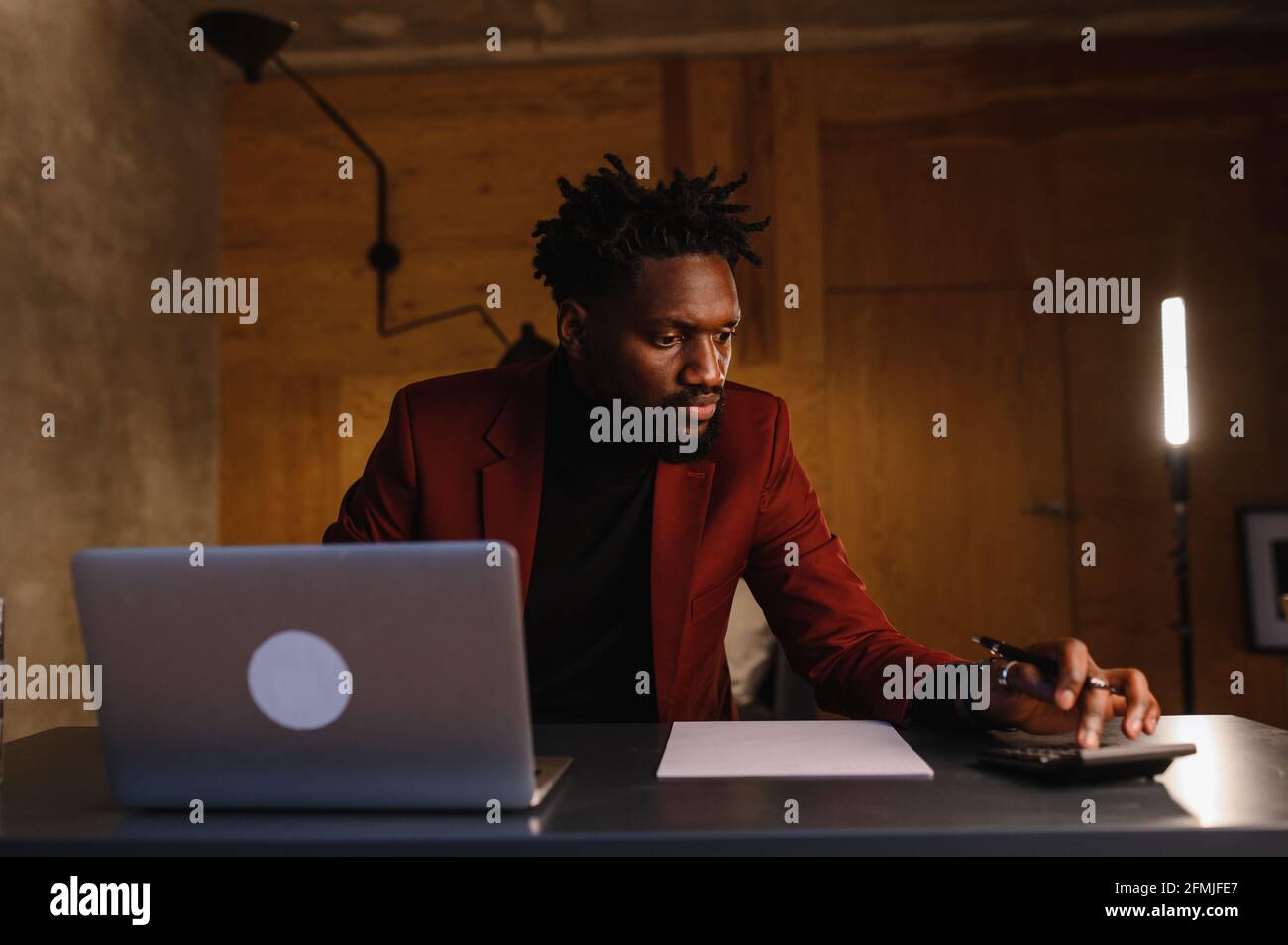 Handsome Black African American Man Working on Laptop Computer while Sitting Behind Desk in Cozy ...