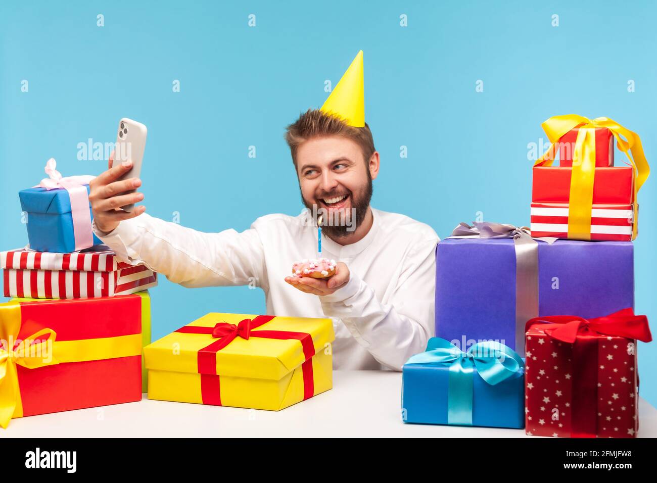 Happy smiling man blogger in cone hat celebrating his birthday with ...