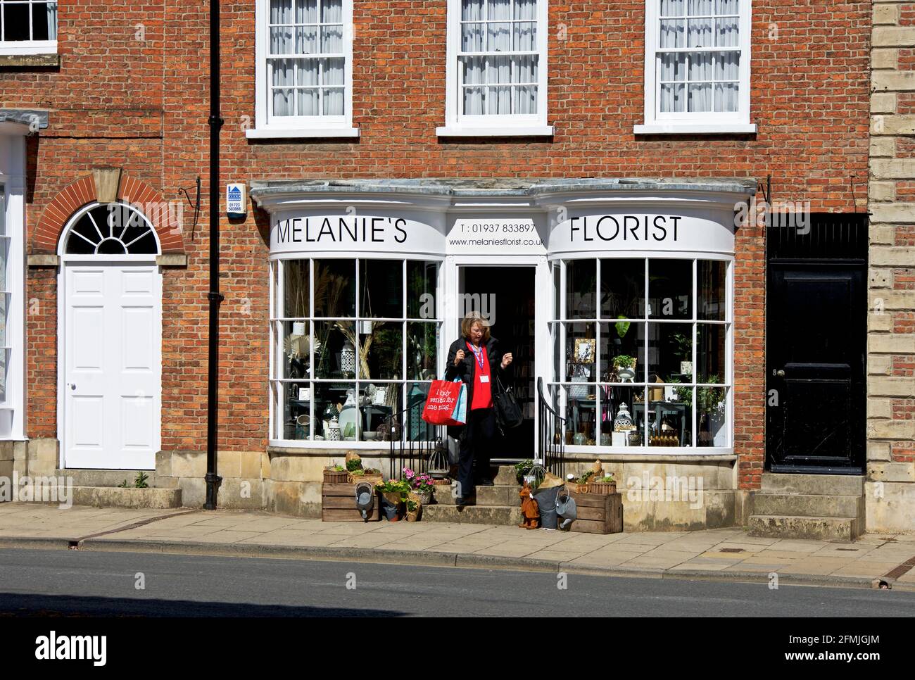 Woman leaving florist shop on Bridge Street, Tadcaster, North Yorkshire ...