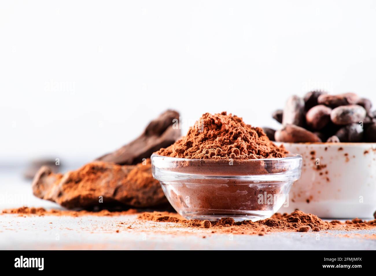 Organic cocoa powder, beans, grated lump on gray background. Copy space ...