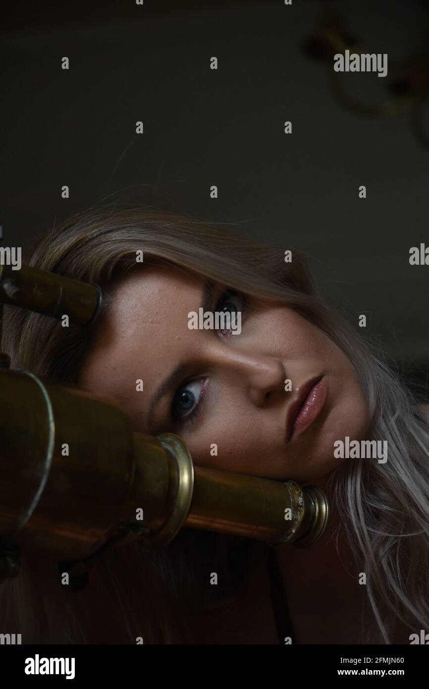Beautiful blonde woman with old brass telescope, close up portrait ...