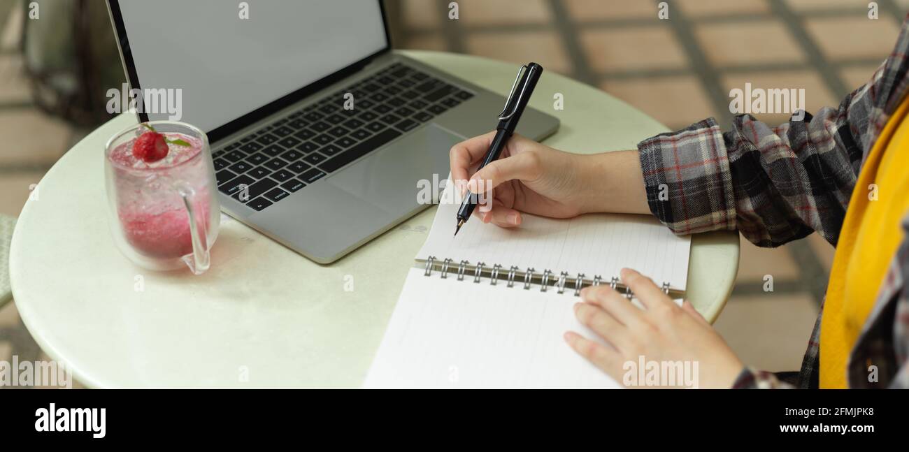 Side view of female freelancer taking note on schedule book while ...