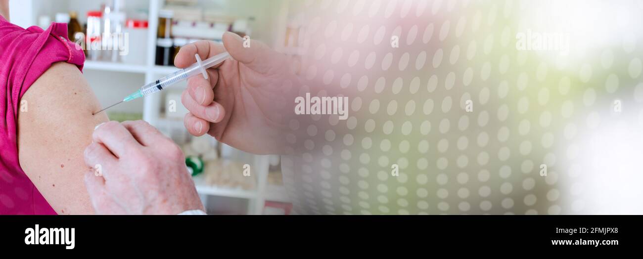 Doctor giving an injection to his patient in medical office; panoramic ...