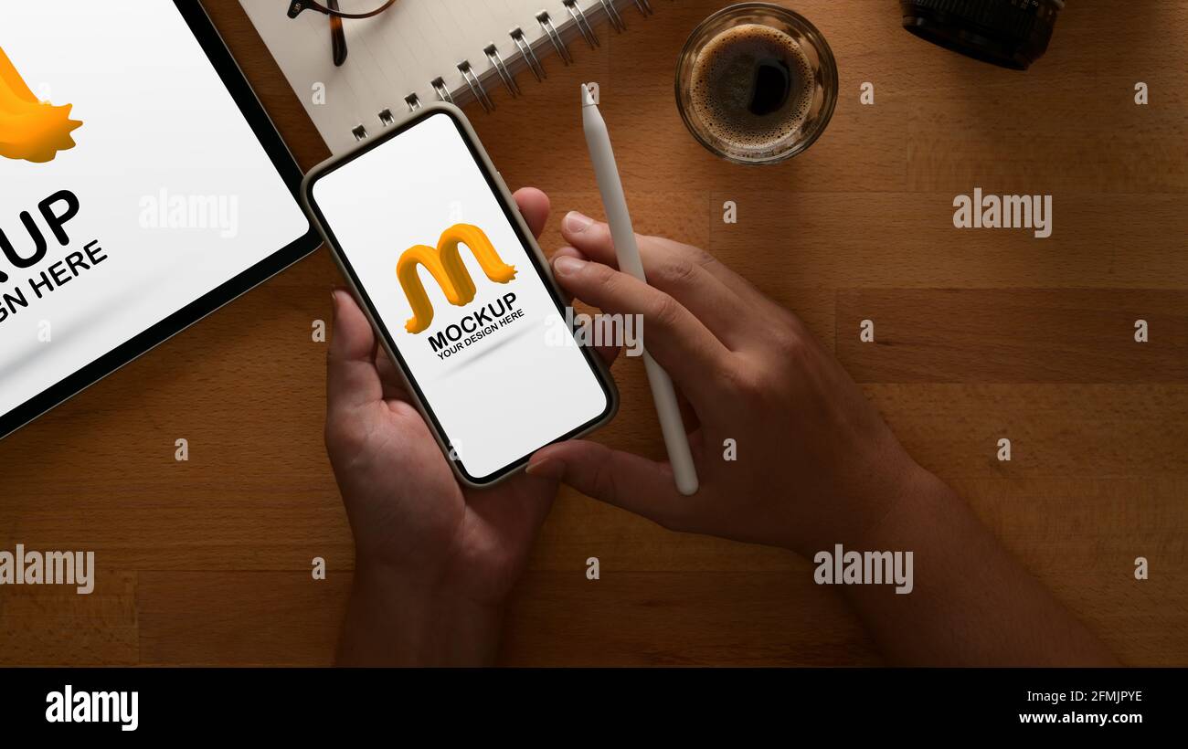 Overhead shot of hands using mock up smartphone on wooden table with ...