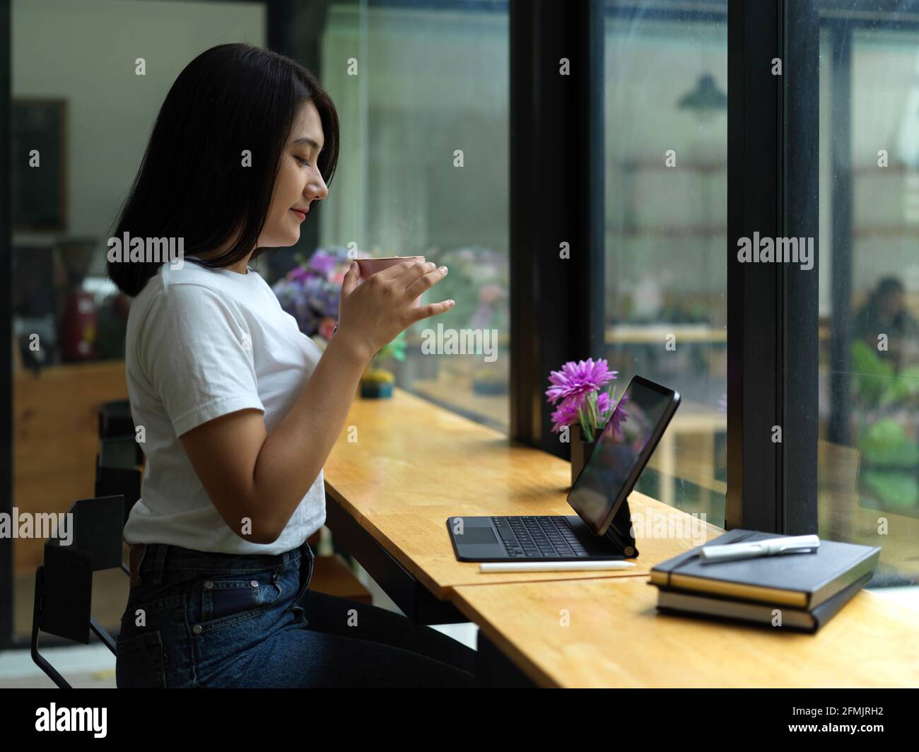Side view of female take a coffee break while working with digital ...