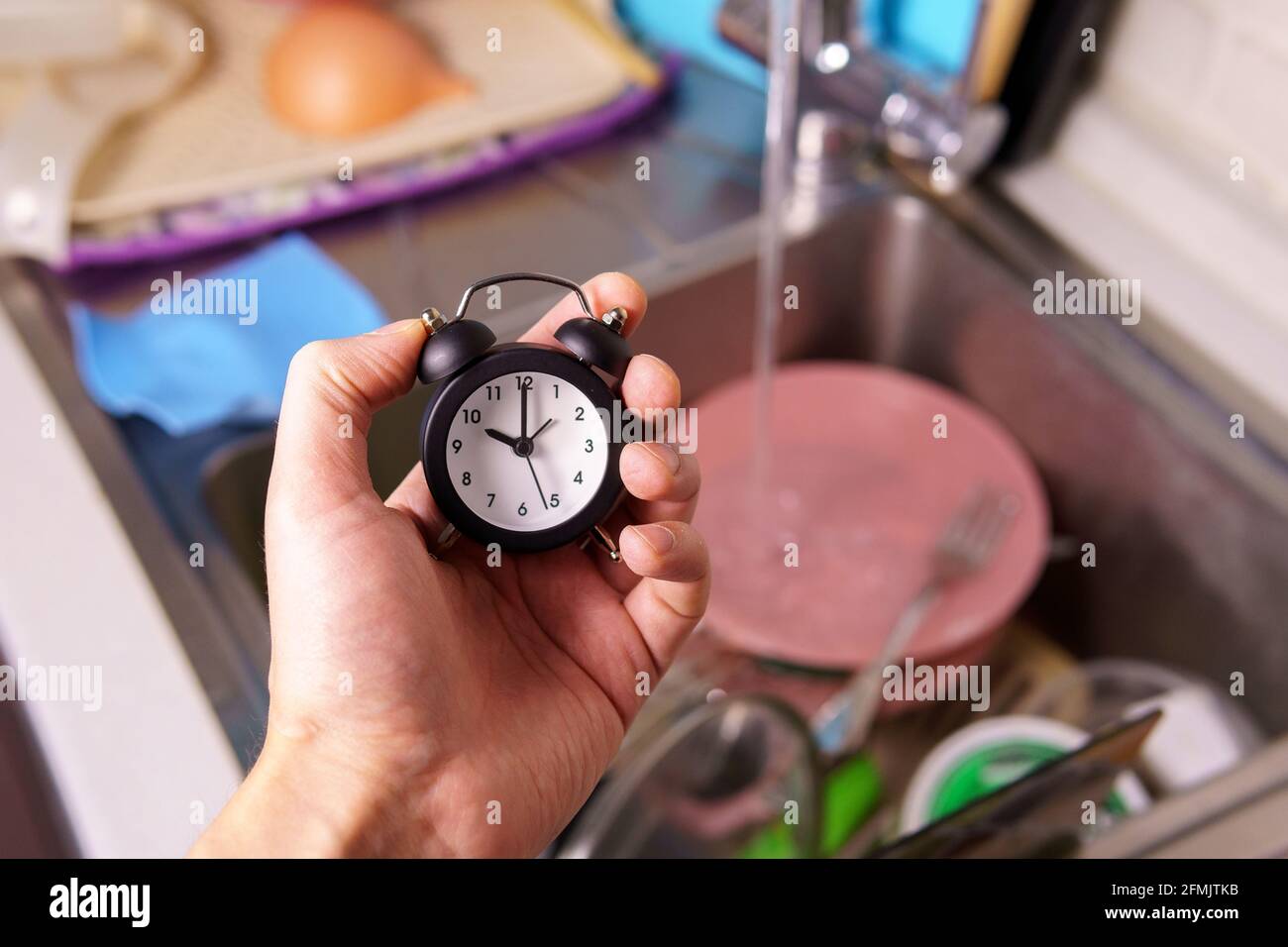 time to wash the dishes. a clock on a blurry background of dirty dishes ...