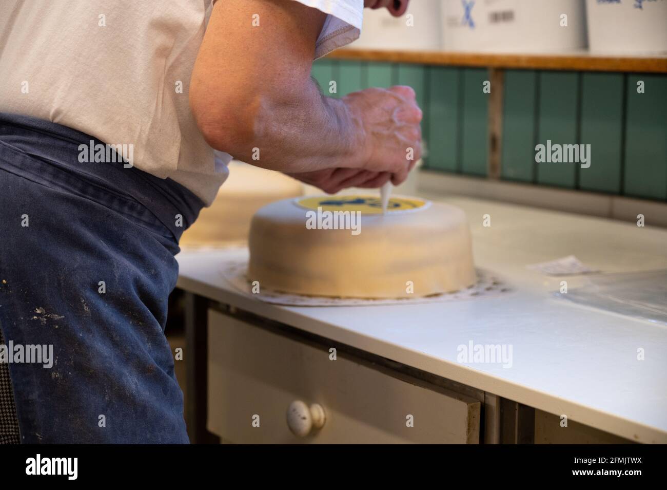 Closeup of a male baker decorating the cake on the table Stock Photo ...