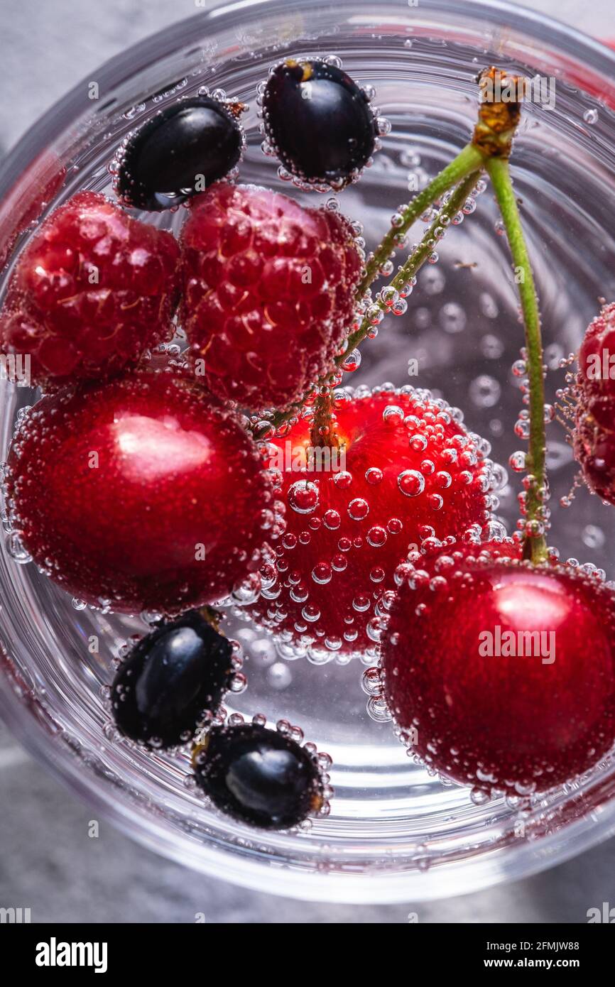 Fresh cold sparkling bubble water drink with cherry, raspberry and ...