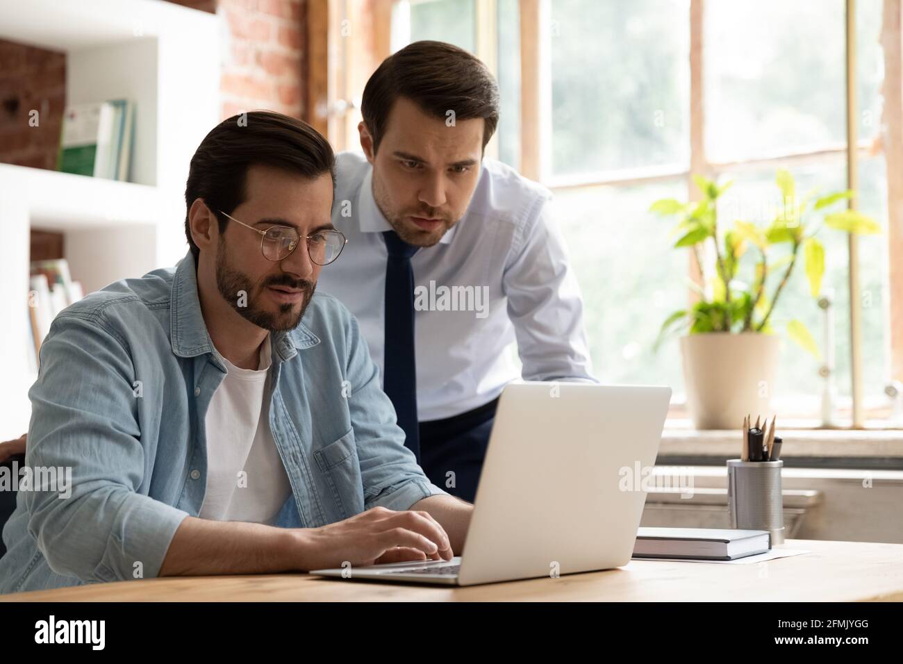Two colleagues employees working on laptop together, using laptop Stock ...