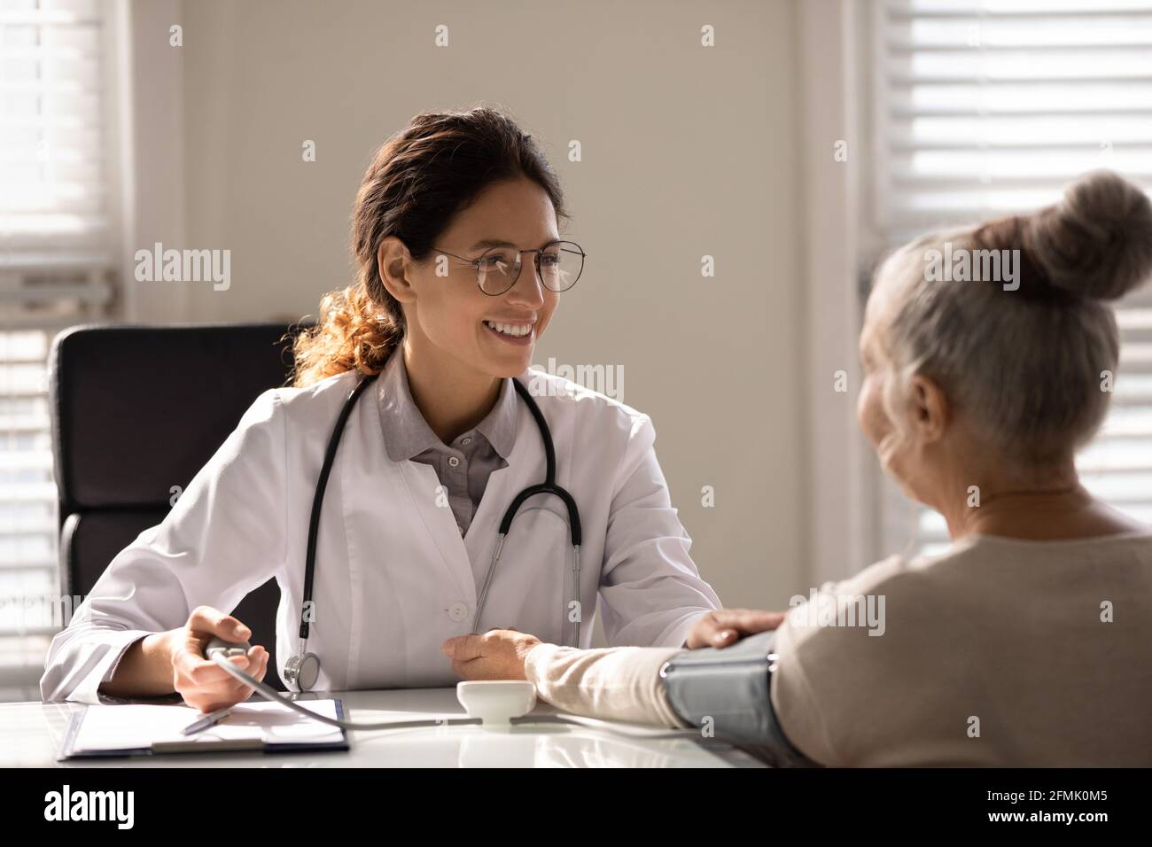 Confident latin female gp measuring tension of aged woman patient Stock ...