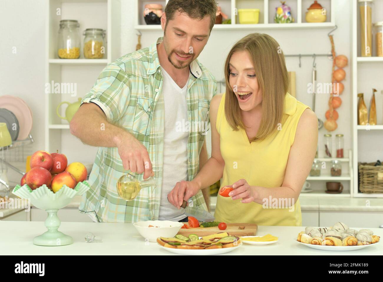 Happy husband and wife cooking together in the kitchen Stock Photo - Alamy